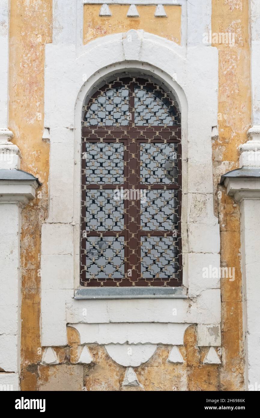 A window with an iron lattice in the stone wall of an old Orthodox ...
