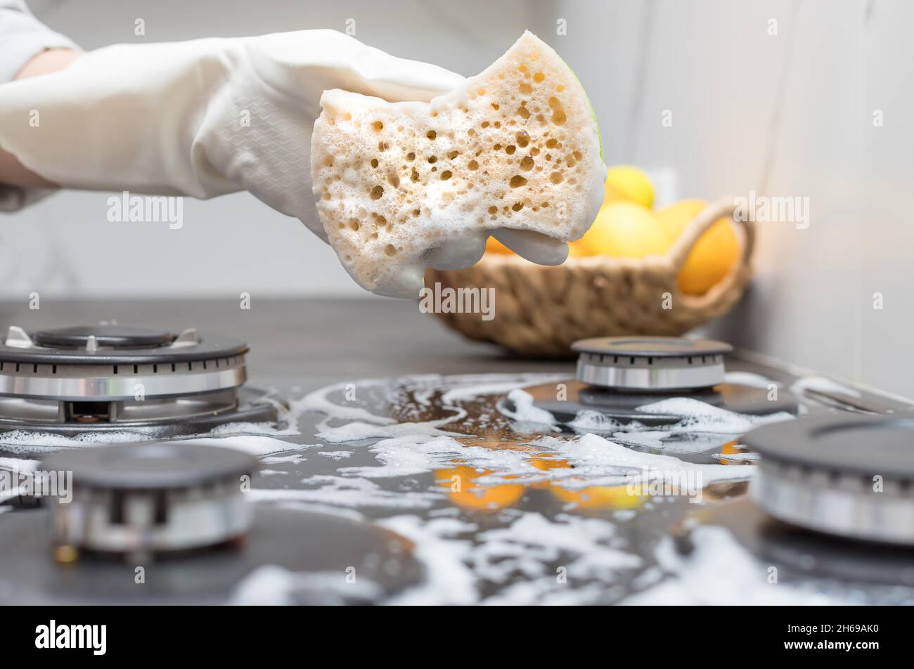 Sponge with foam in hand, near gas stove Stock Photo - Alamy