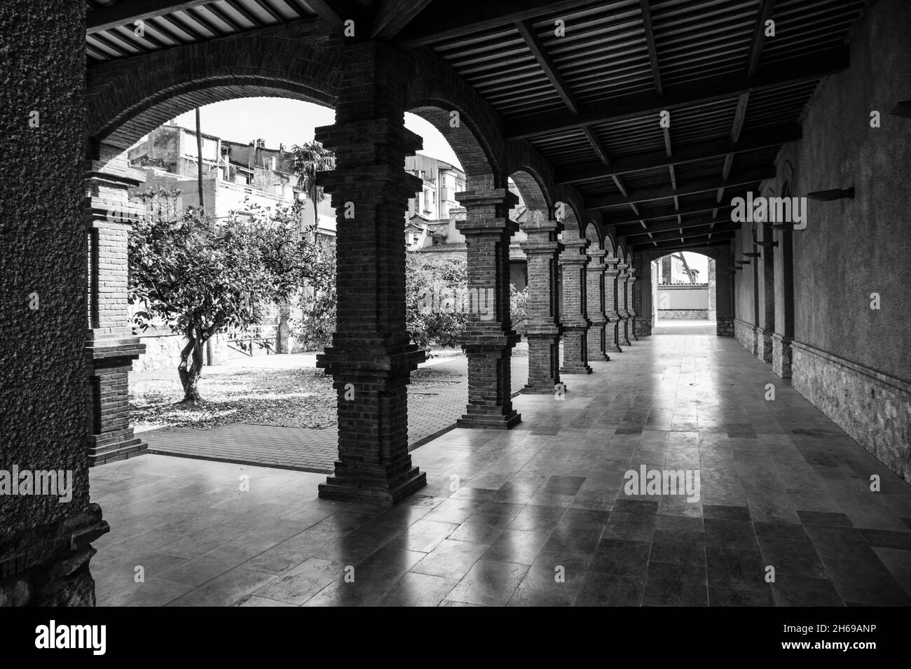 A grayscale shot of a building with brick columns and arches Stock ...