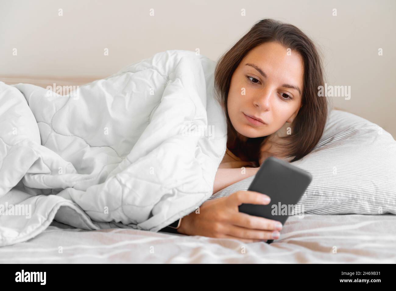 Young woman goes to sleep Phone addiction, insomnia. try to fall asleep ...