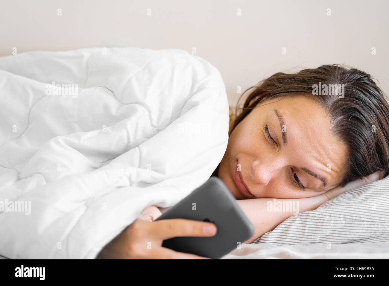 Young woman goes to sleep Phone addiction, insomnia. try to fall asleep ...