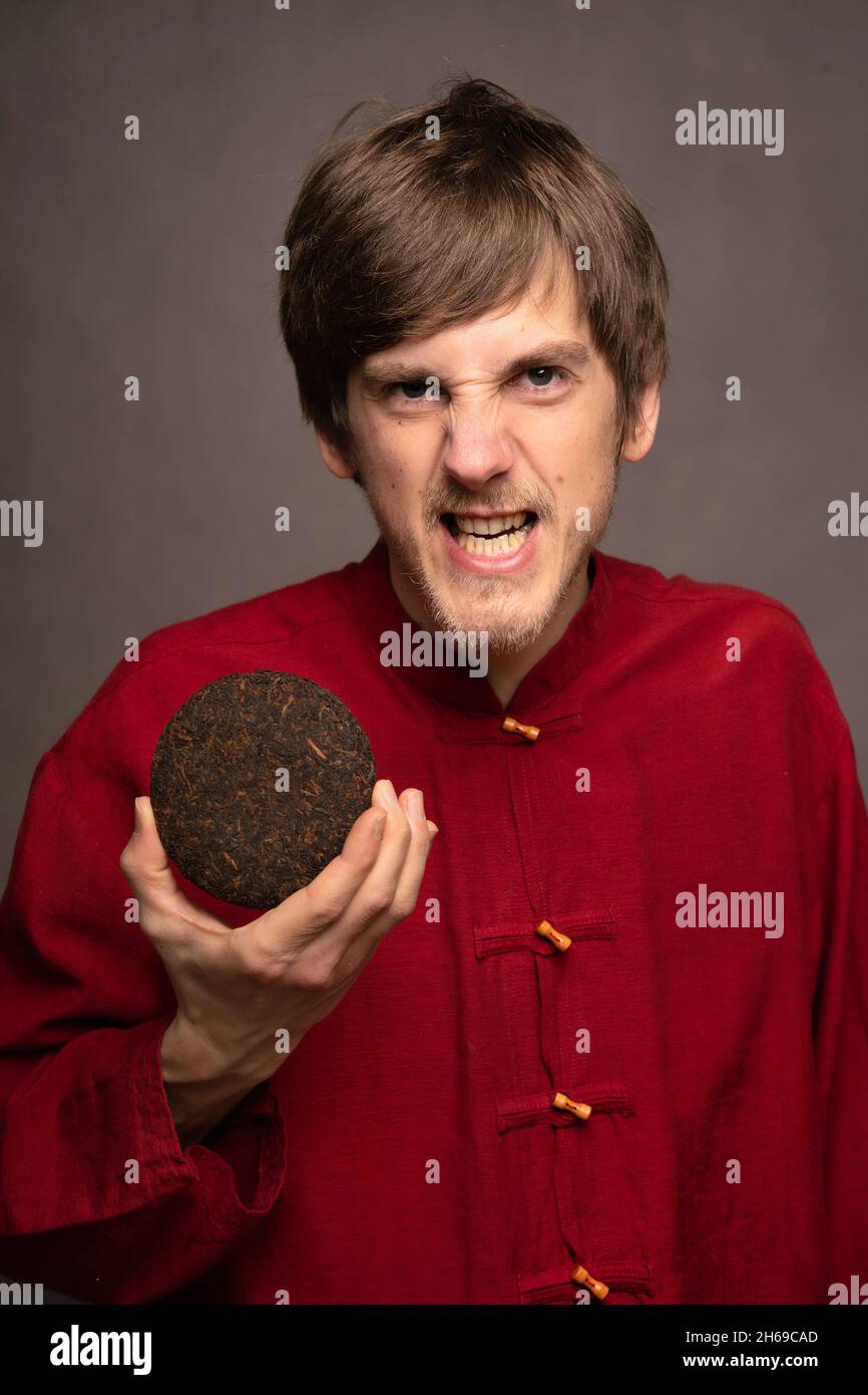 Young handsome tall slim white man with brown hair angry holding pu erh ...