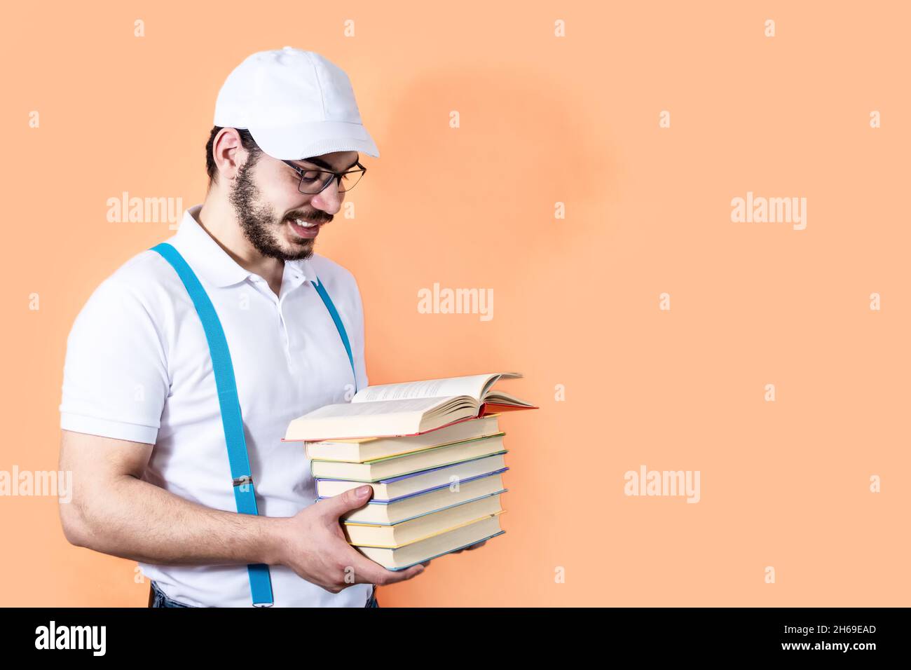 Ready to study hard. Young man holding a stack of books on a light ...