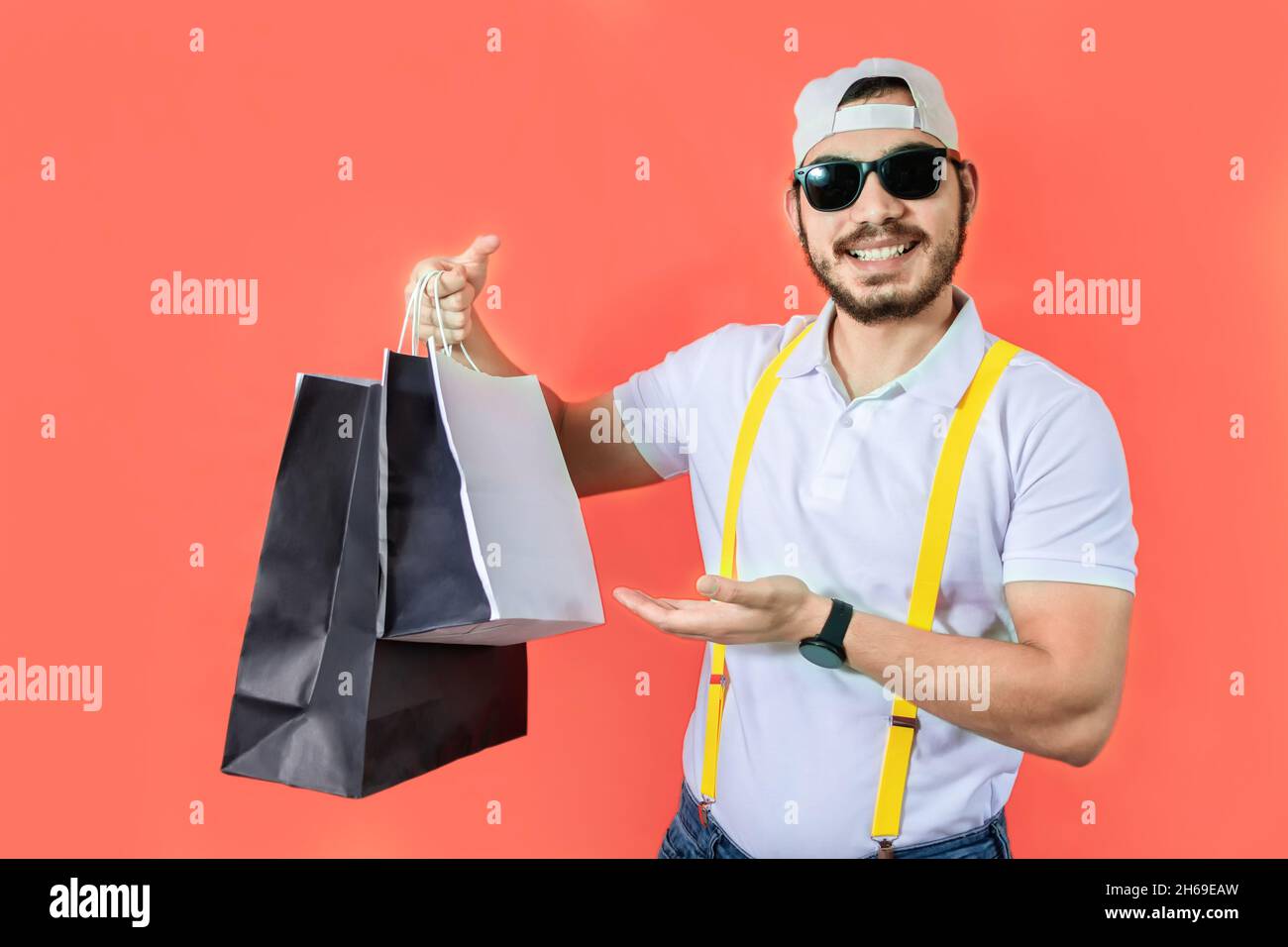 A hipster guy with shopping bags; a front view in the orange background ...