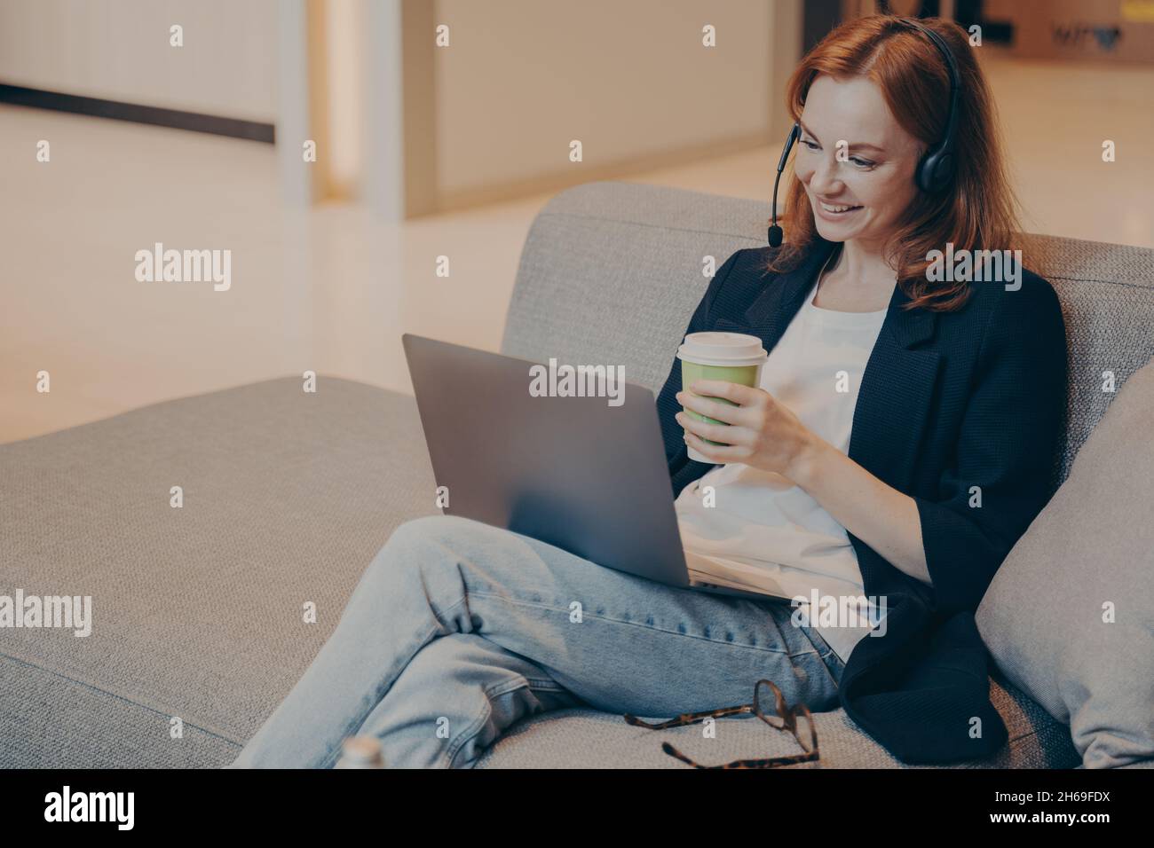 Smiling young female call center agent in wireless headset and laptop ...