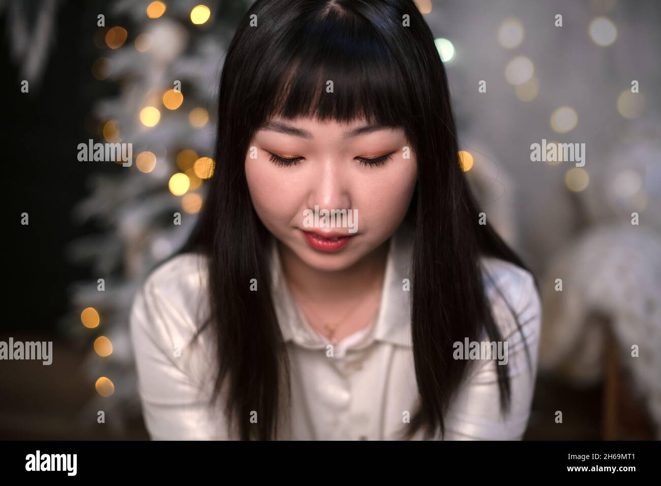 A young, beautiful Korean Asian woman with modestly lowered eyes is in ...