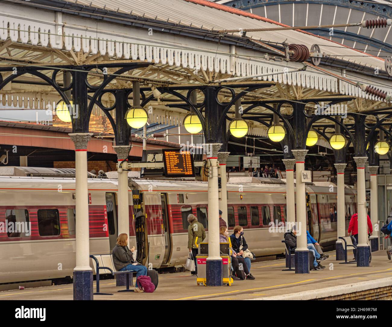 Railway station platform with passengers waiting for a train. Overhead ...