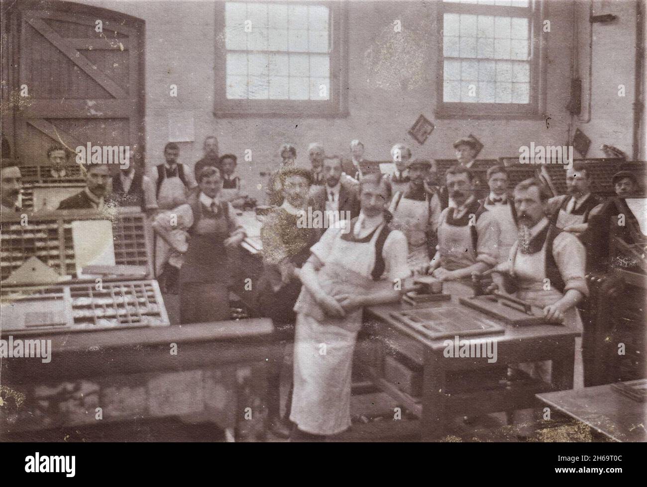 Printing workers posing in workshop, trays of movable type can be seen ...