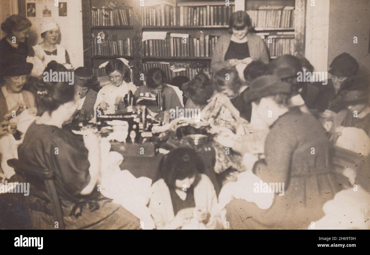 Group of women sewing together around a table, most are hand sewing but ...