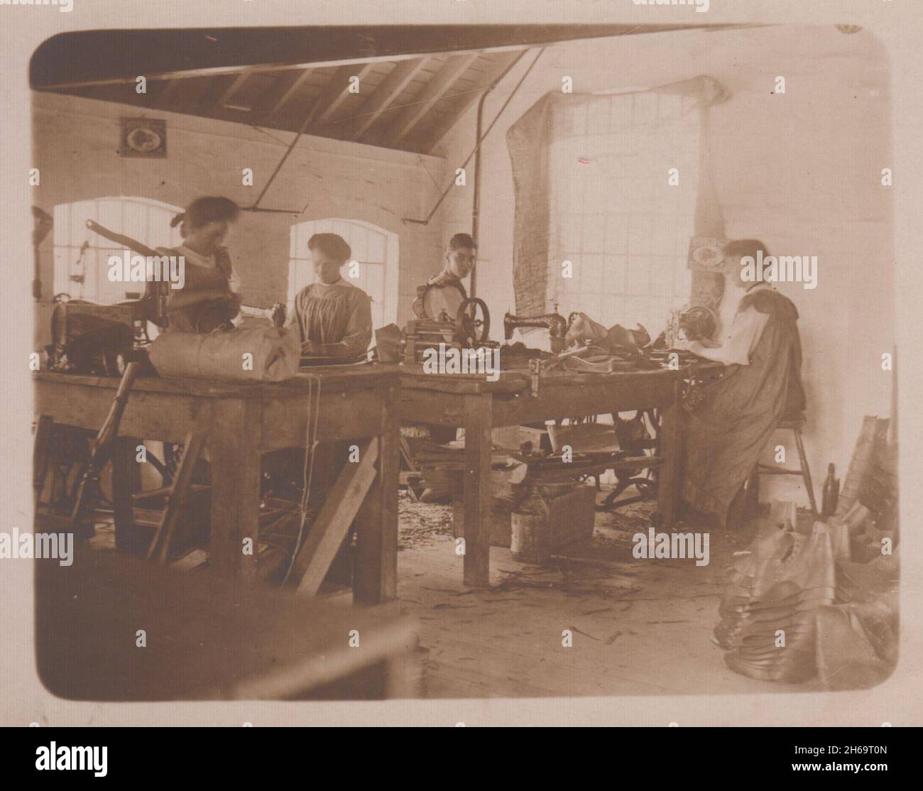 Women bootmakers machining the leather uppers of boots in an untidy ...