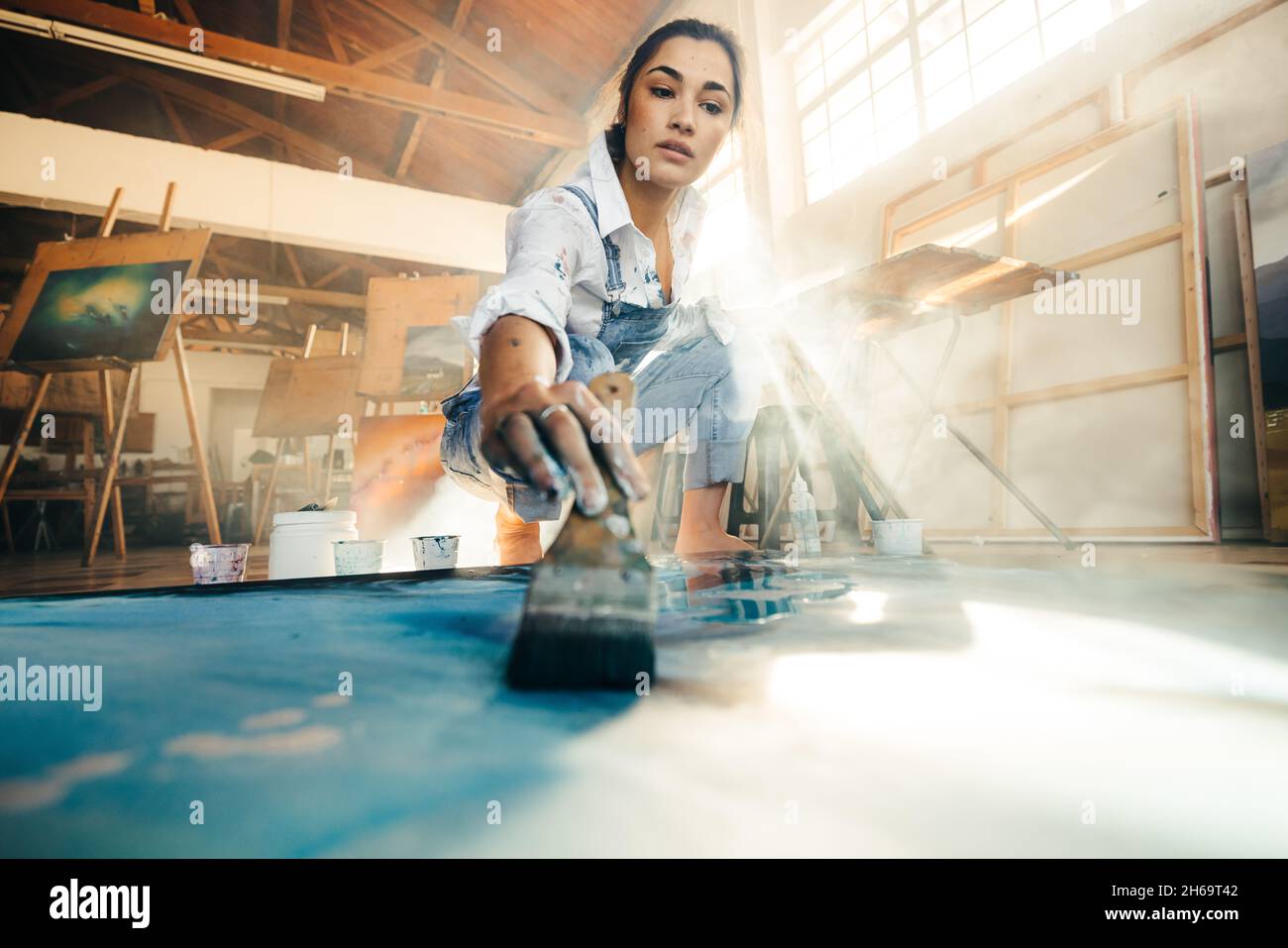 Skilful young artist painting on a canvas with a paintbrush. Female ...
