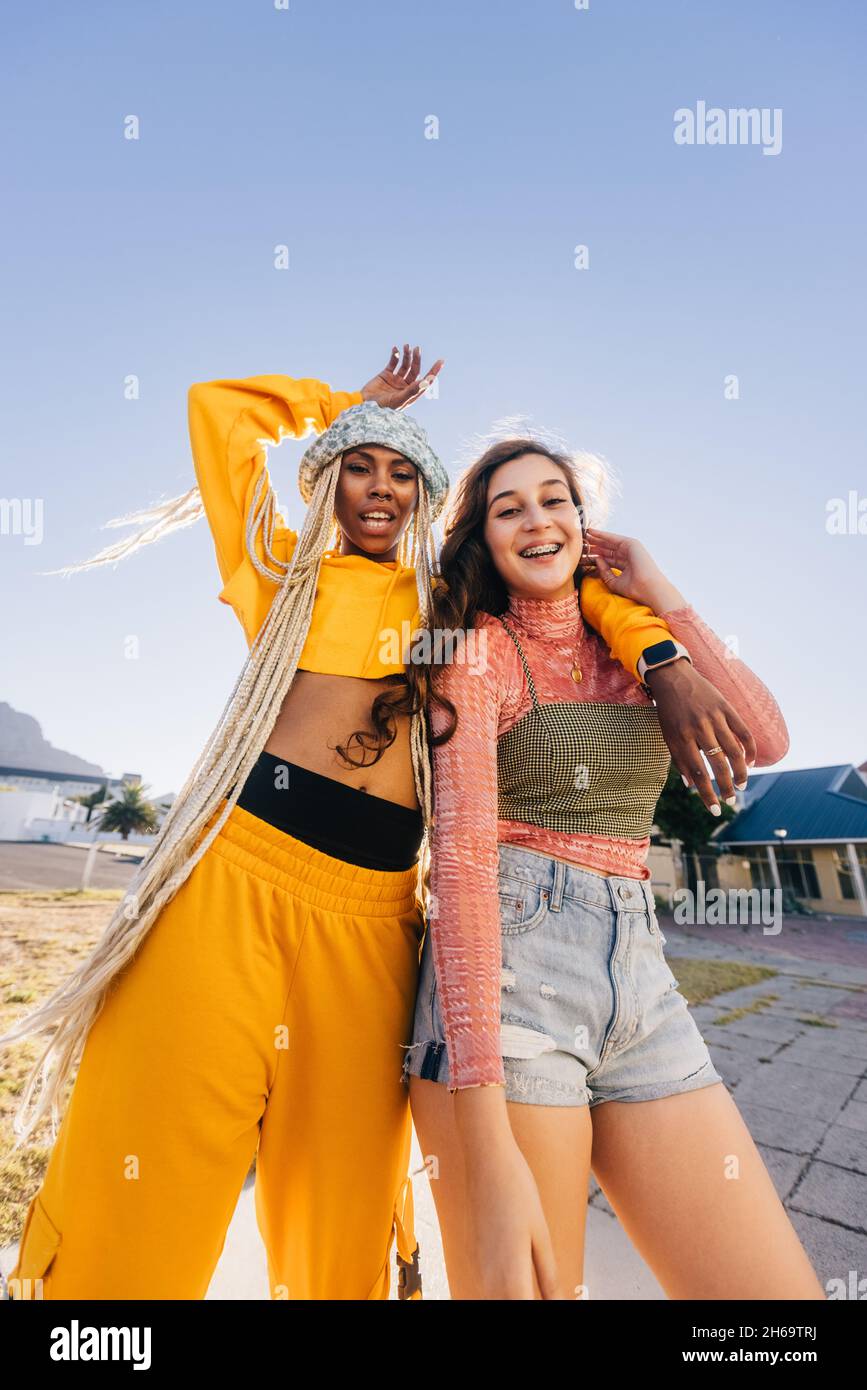 Two happy girls smiling at the camera while standing together outdoors ...
