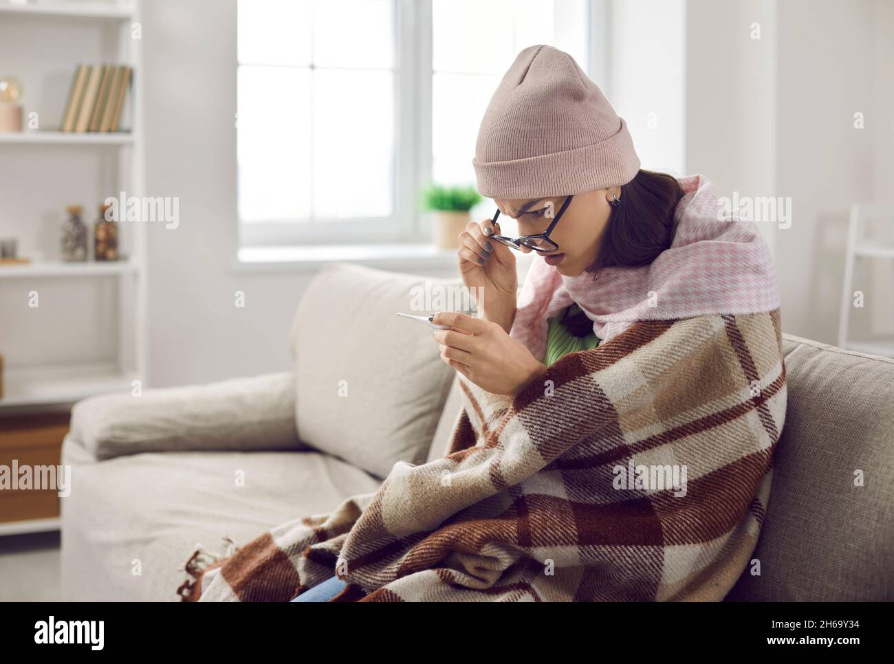 Sick woman who has flu takes her temperature and looks at thermometer ...