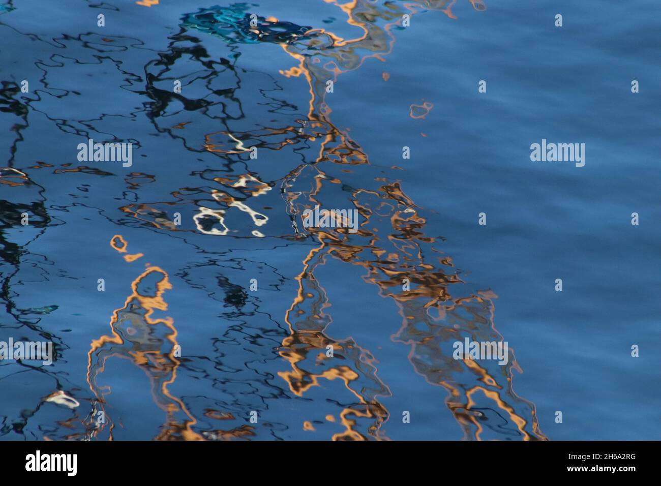 Shapes and colours in reflections of fishing boats in water of harbour ...