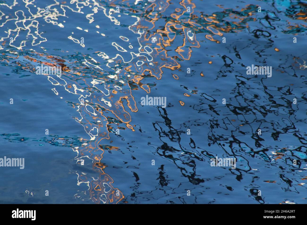 Shapes and colours in reflections of fishing boats in water of harbour ...