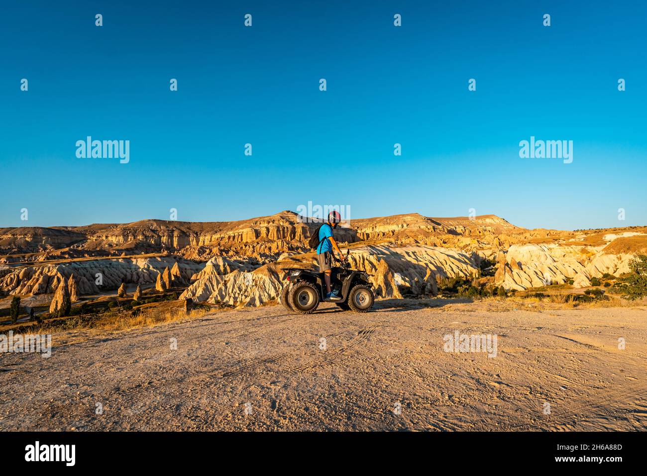 A tourist riding a quad bike in a valley surrounded by rock formations ...