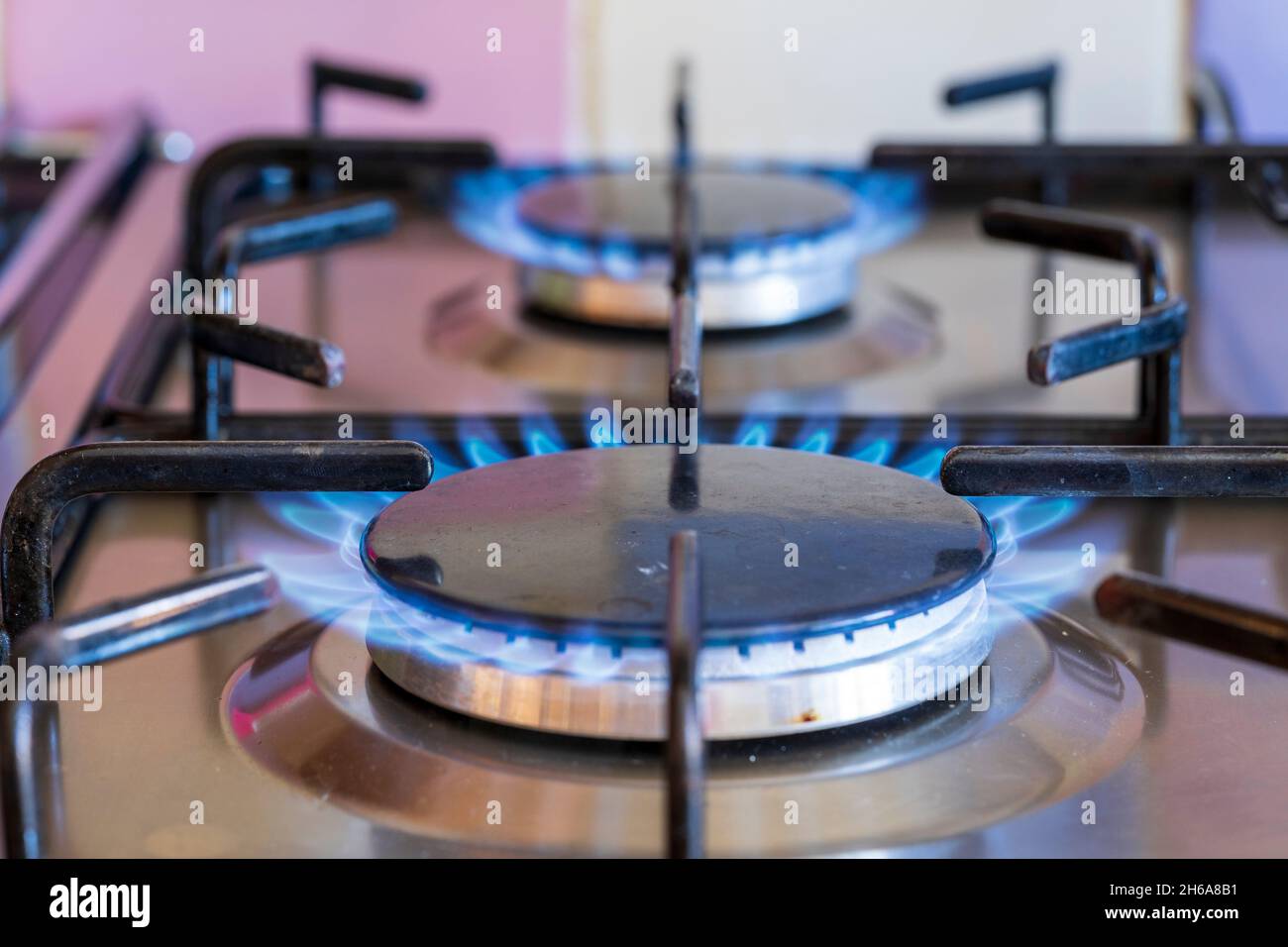 Gas ring alight on gas cooker hob. Circular grey ring topped with cast ...