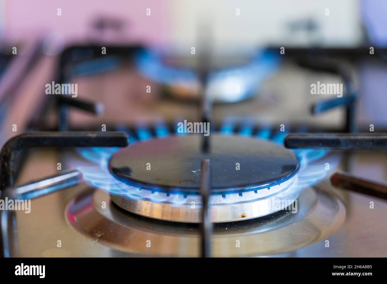 Gas ring alight on gas cooker hob. Circular grey ring topped with cast ...