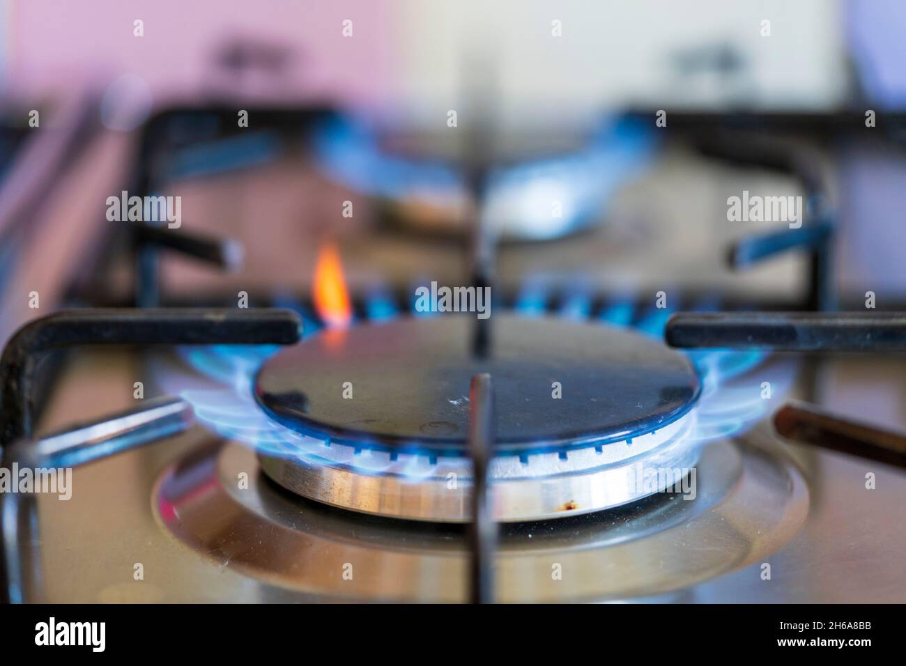 Gas ring alight on gas cooker hob. Circular grey ring topped with cast ...