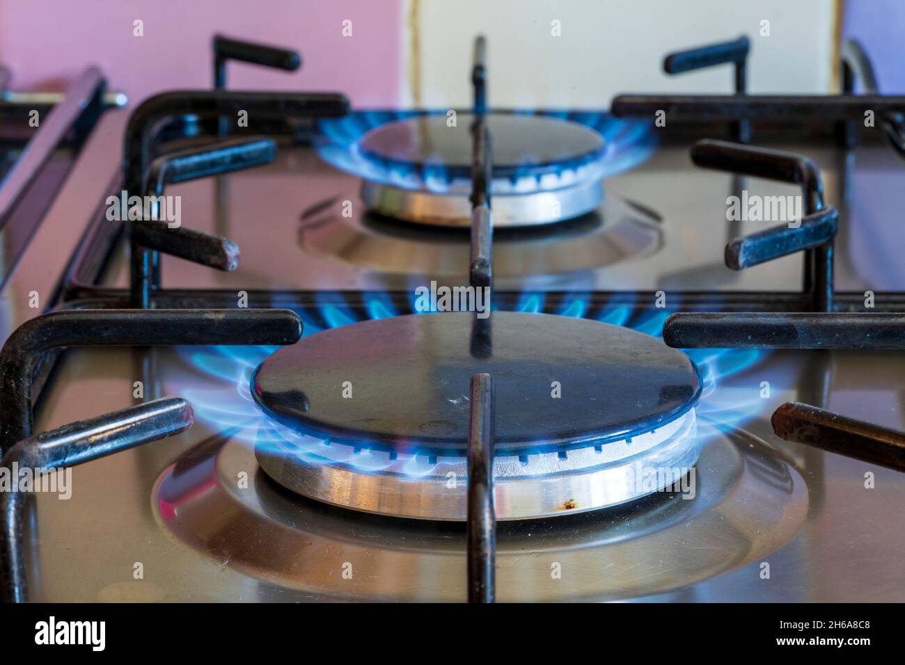 Gas ring alight on gas cooker hob. Circular grey ring topped with cast ...