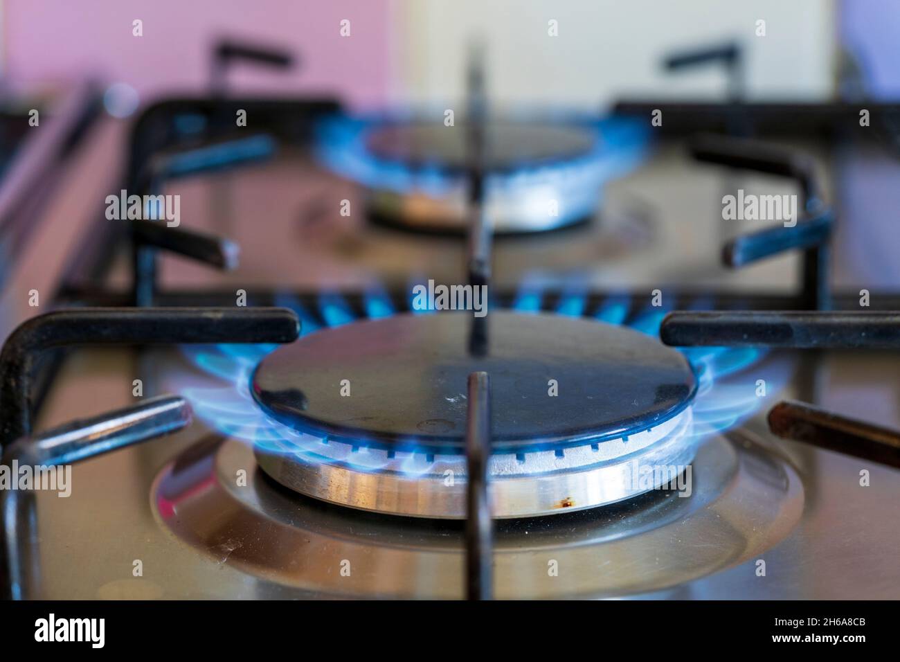 Gas ring alight on gas cooker hob. Circular grey ring topped with cast ...