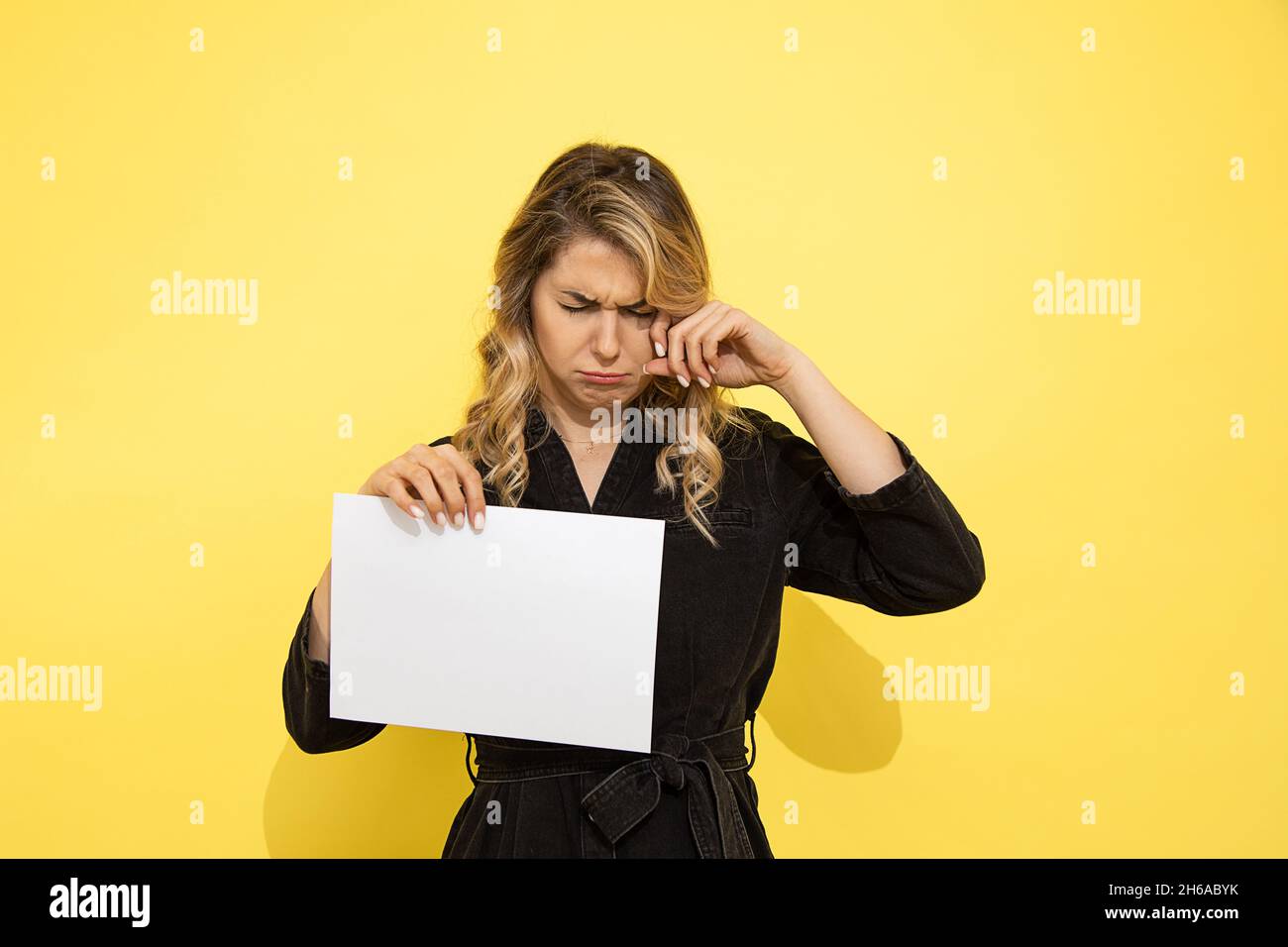 Portrait of young woman is upset, wiping tear crying holding in hand ...