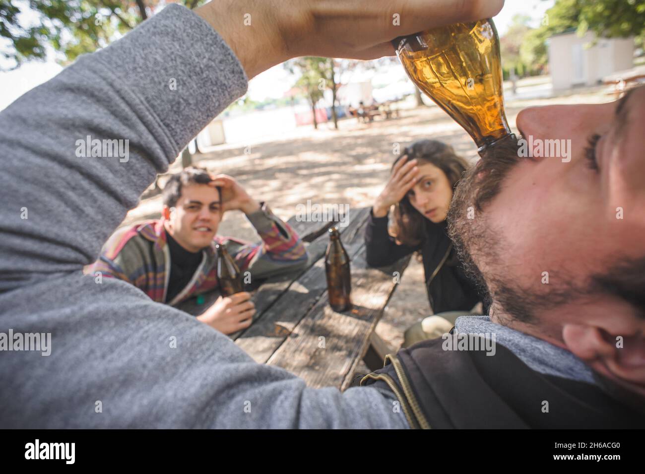 Young group of friends, female and male, chugging beer from bottle on ...