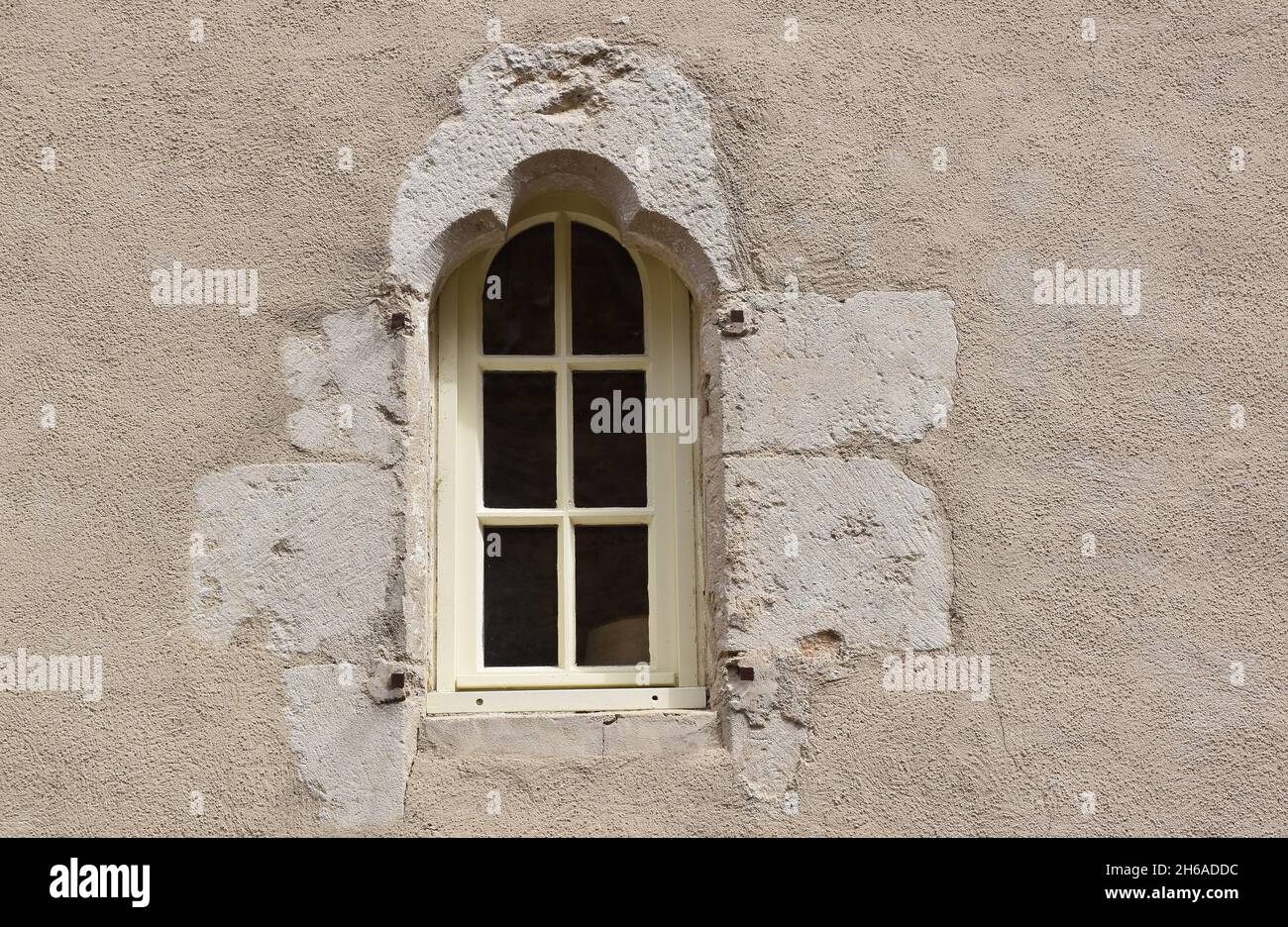 A small window with a carved trefoil head and cream-painted 6-light ...