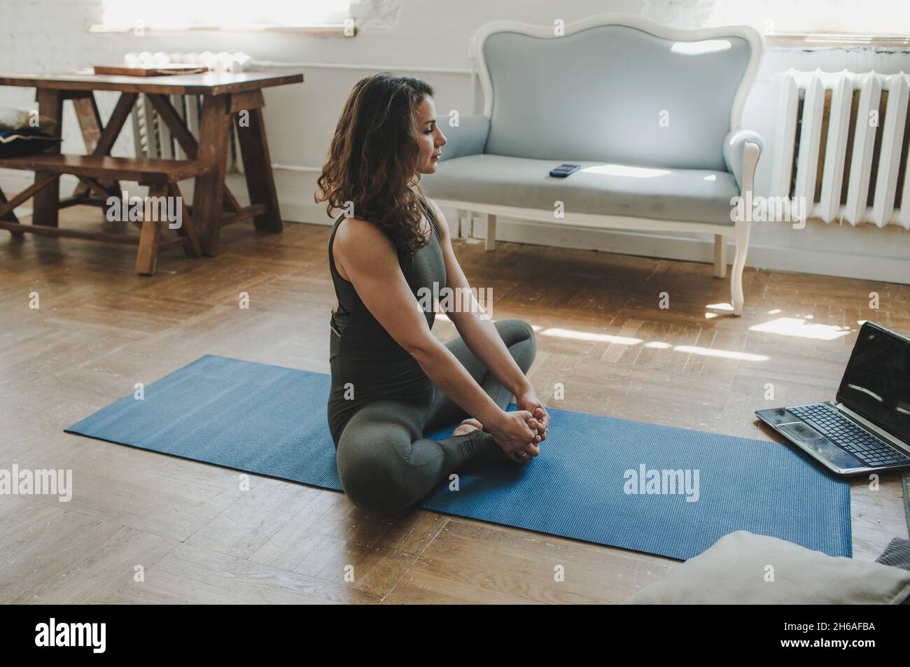 A young woman does sports at home. A cheerful athlete with black hair ...