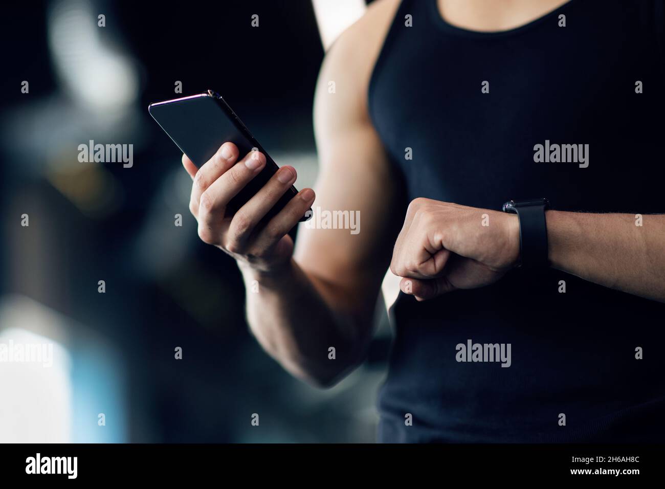 Young Male Athlete Using Smartwatch And Fitness App On Smartphone To ...