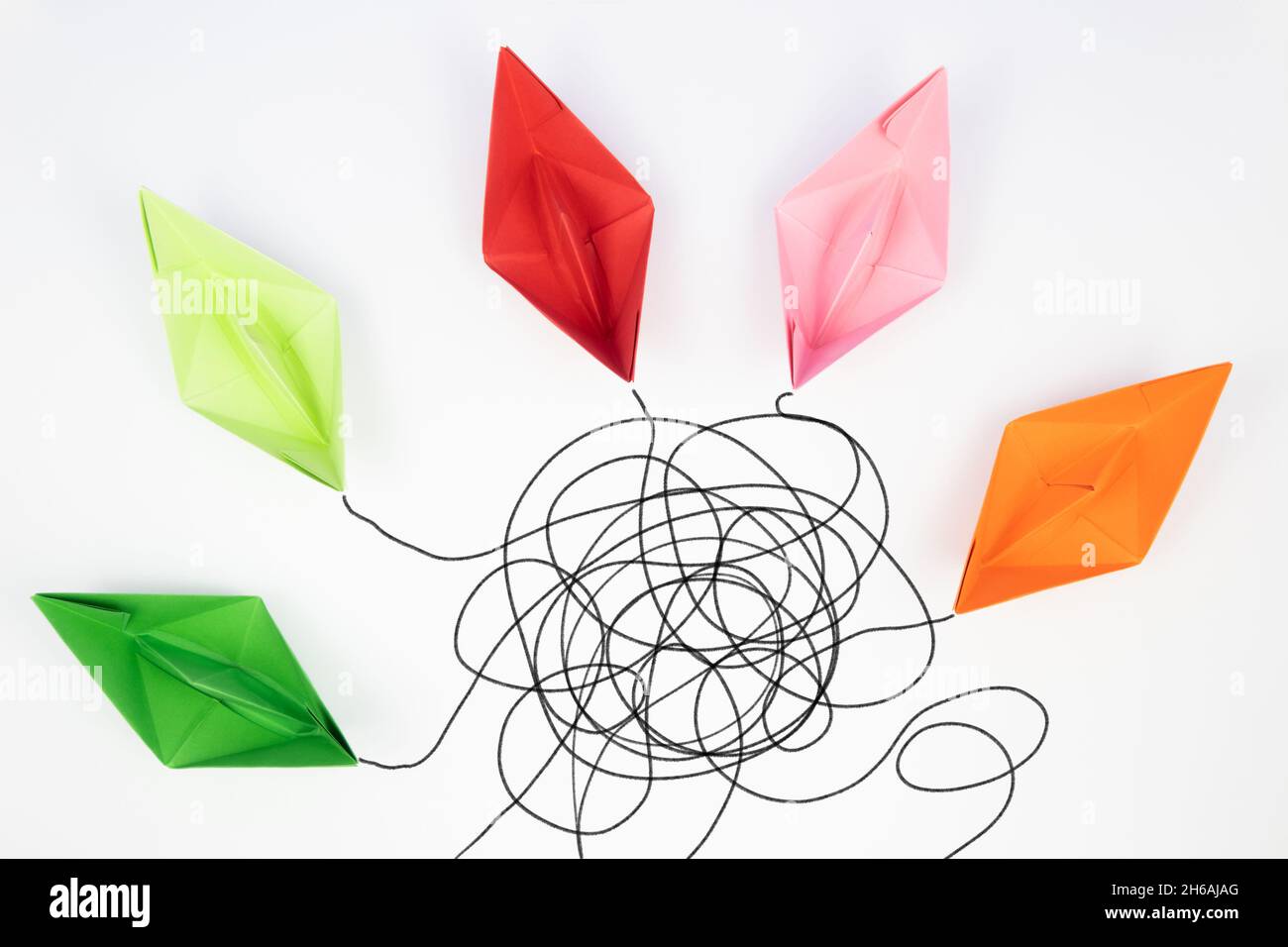 A top view closeup of small colorful paper boats on a white background ...
