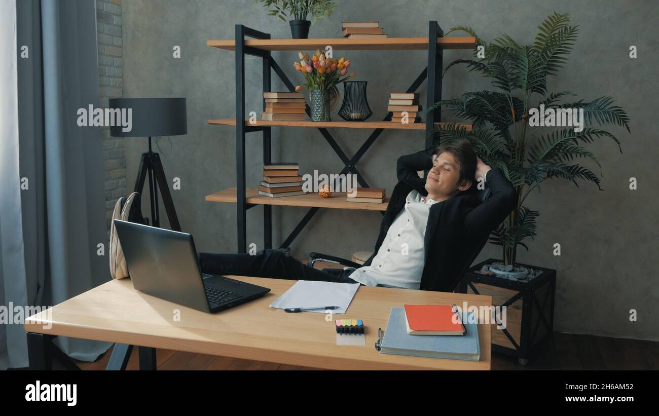 Young attractive businessman is resting from work with his legs on the ...