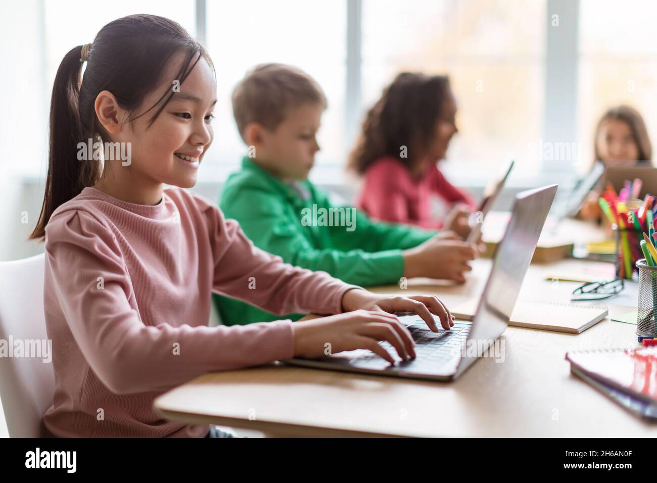 Online Learning. Diverse Children Using Laptop In Modern Classroom At ...