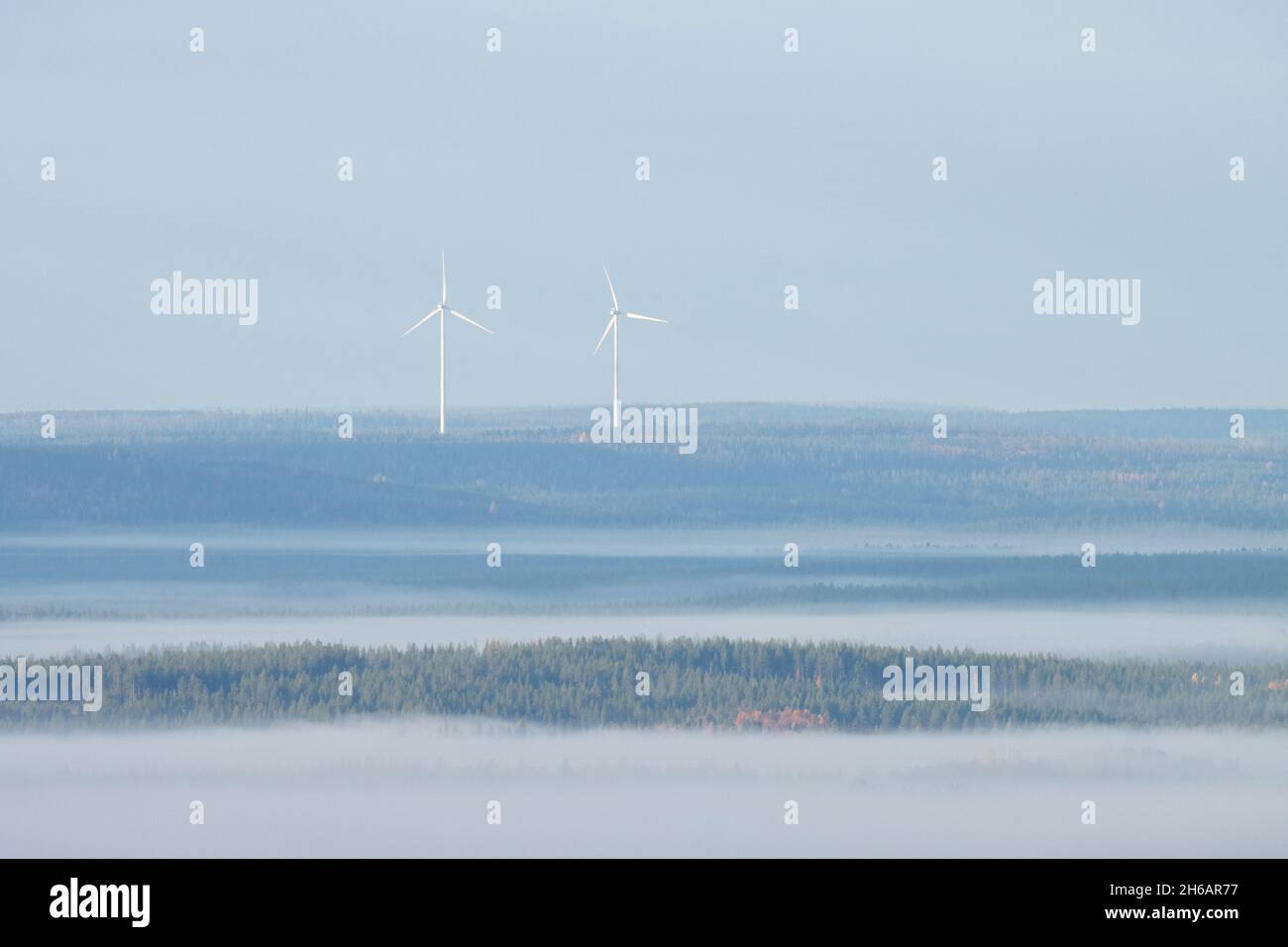 Two wind turbines working in Northern Finland during a foggy morning ...
