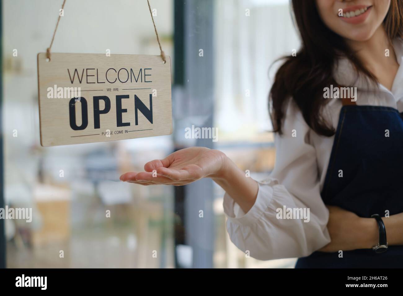 Woman owner with smile turning a sign from closed to open. sme concept ...