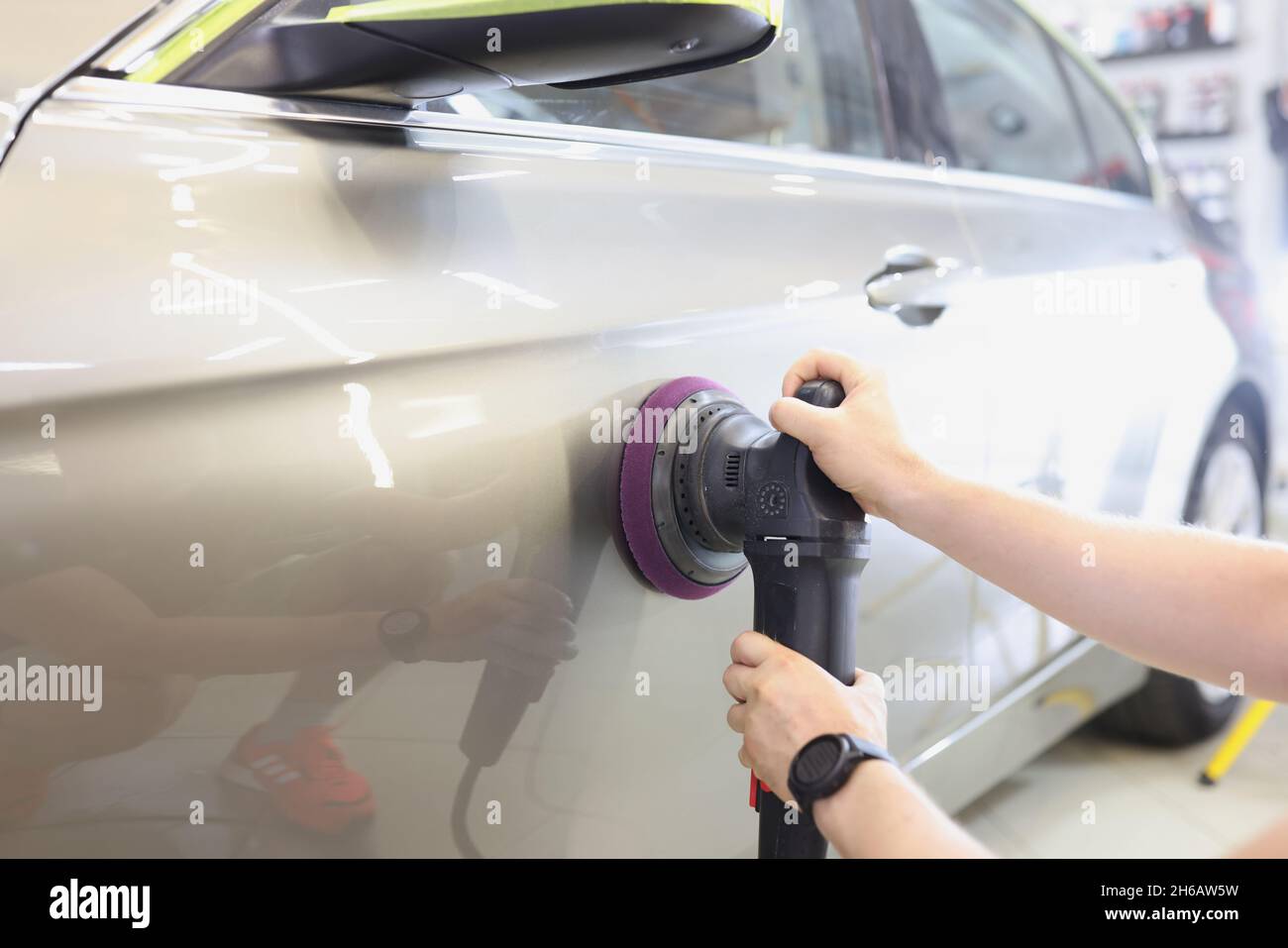 Craftsman polishes car door with eccentric sander in car service ...