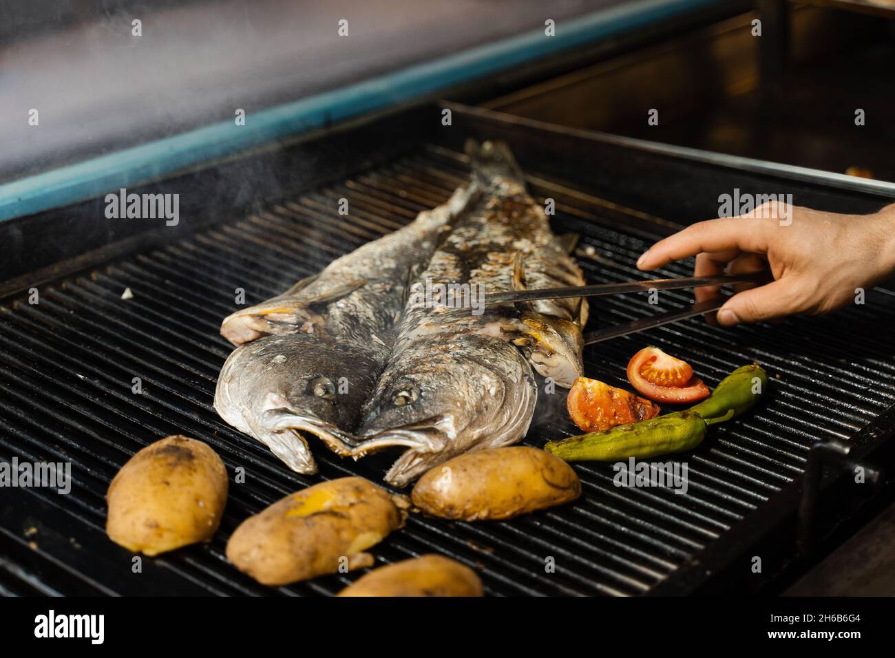 Cooking sea bass and vegetables. Grilling fish with chili potatoes and ...