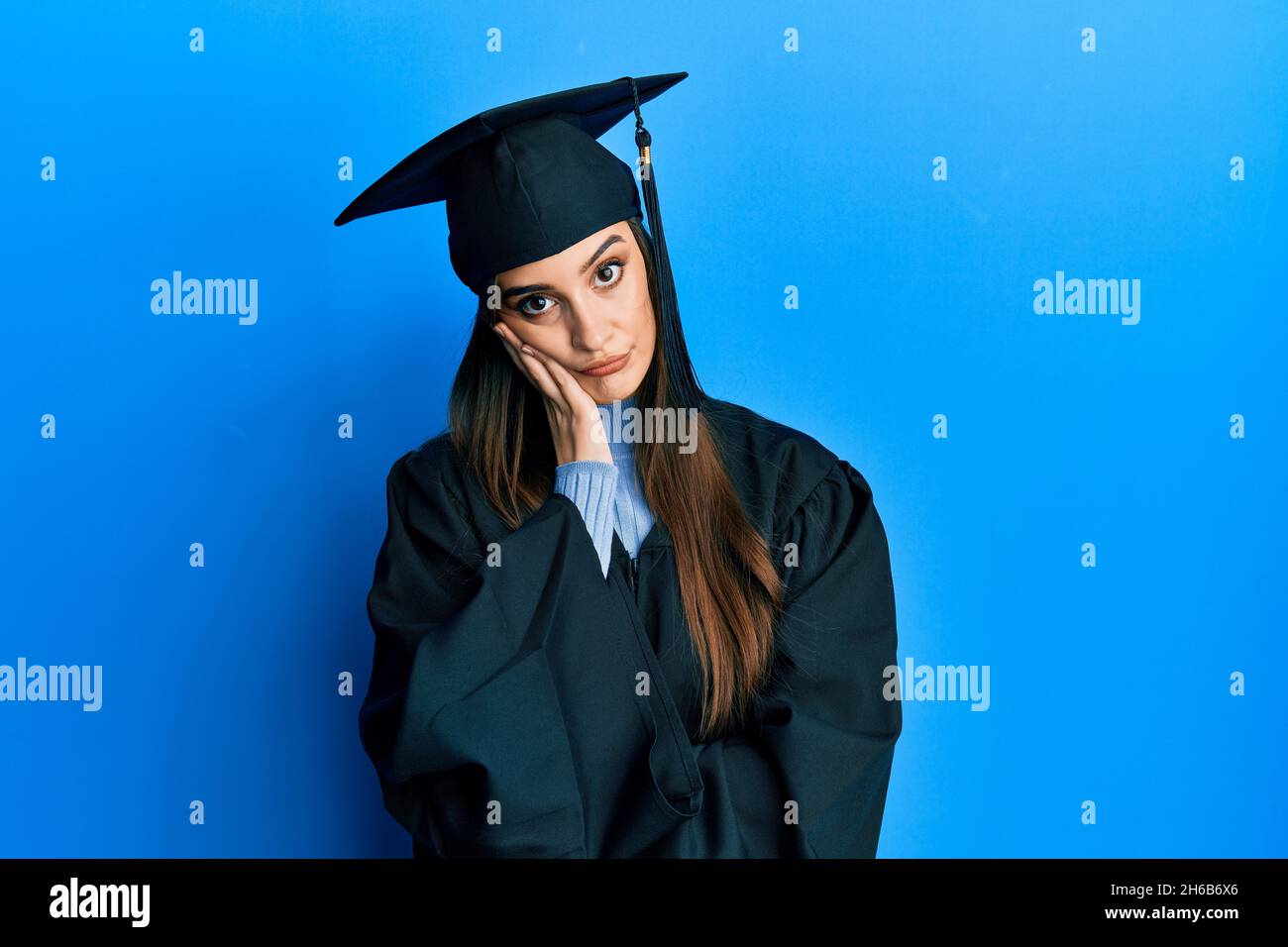 Beautiful brunette young woman wearing graduation cap and ceremony robe ...