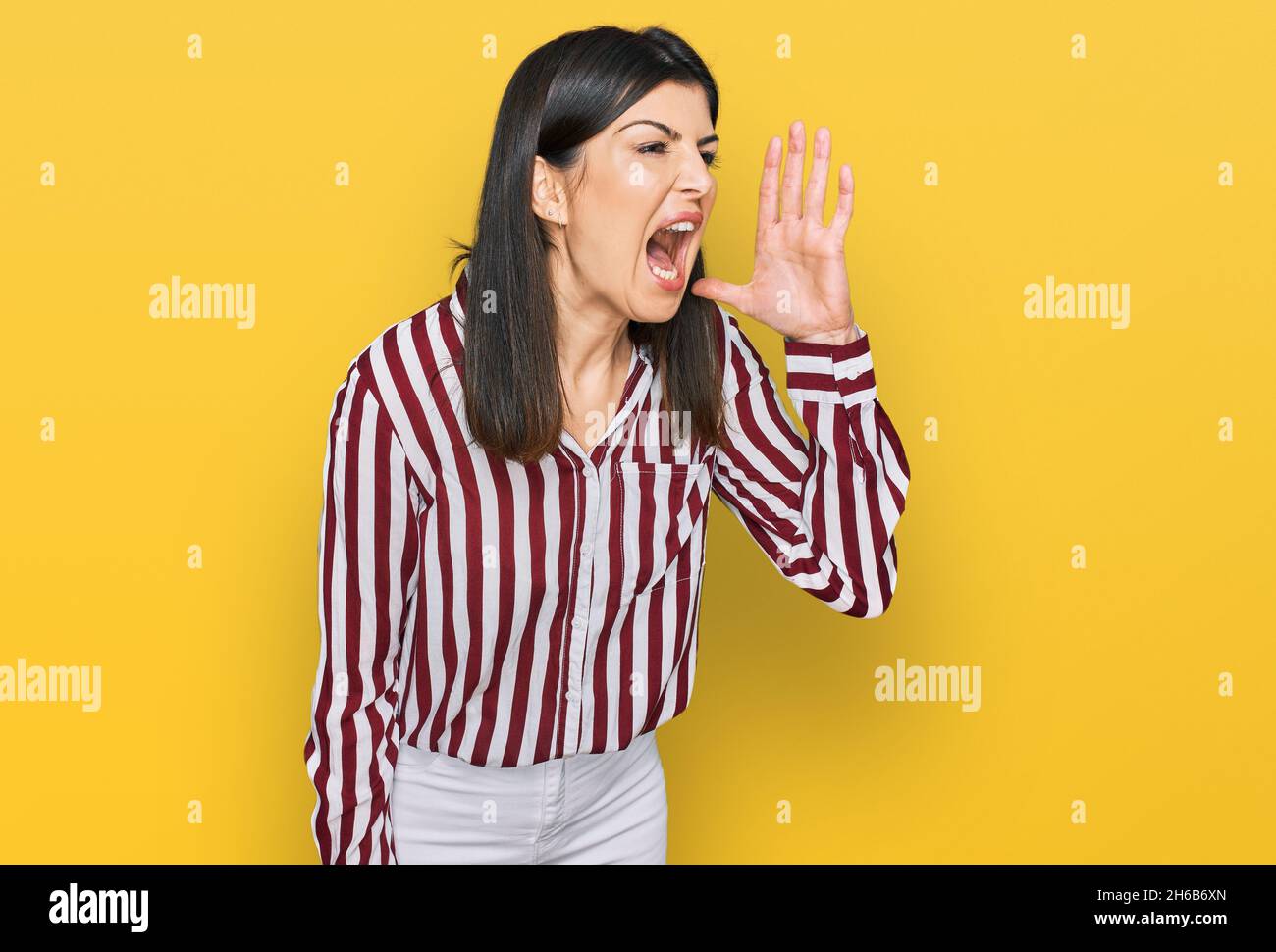 Beautiful brunette woman wearing striped shirt shouting and screaming ...