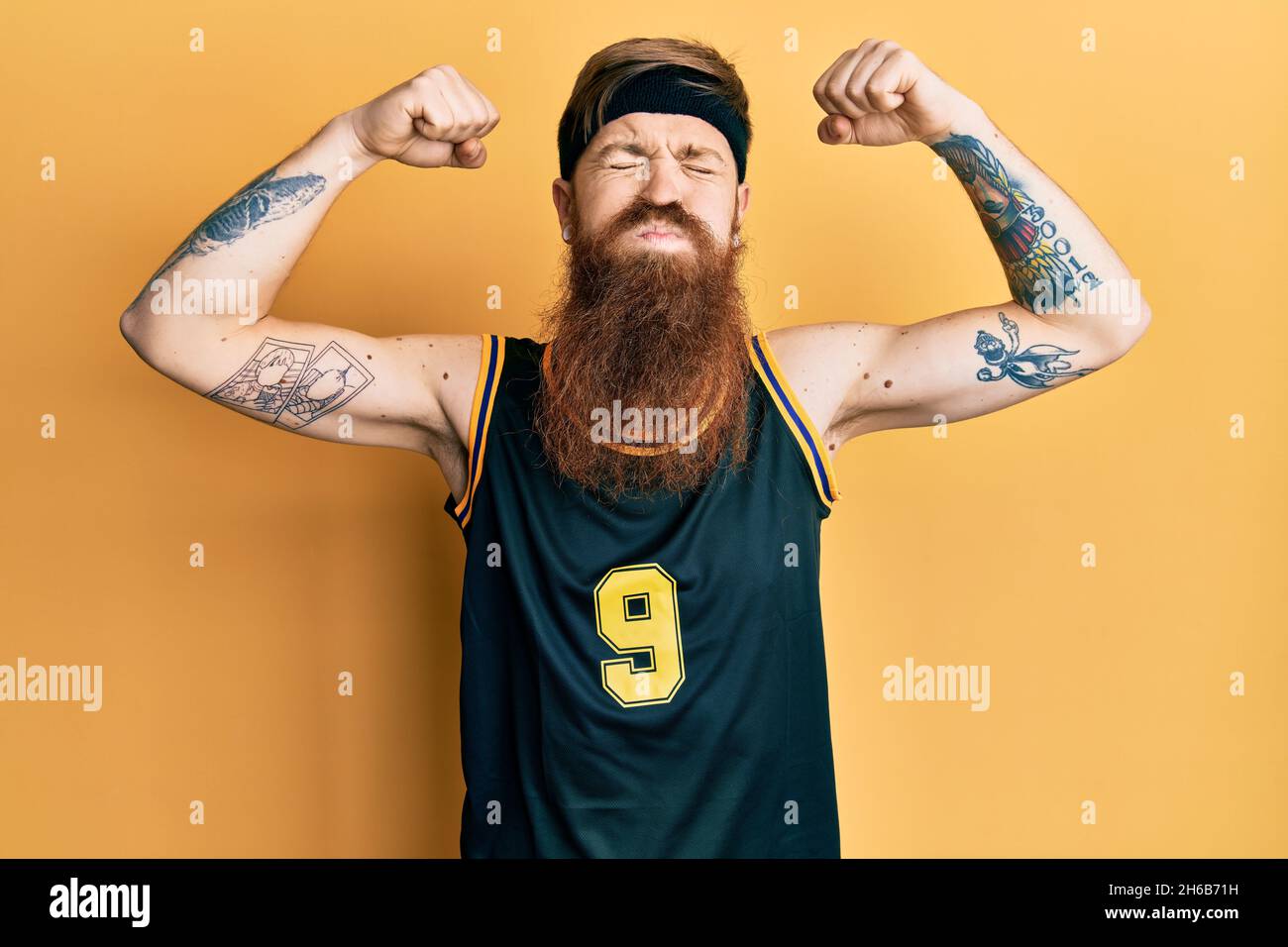 Redhead man with long beard wearing basketball uniform showing muscles ...