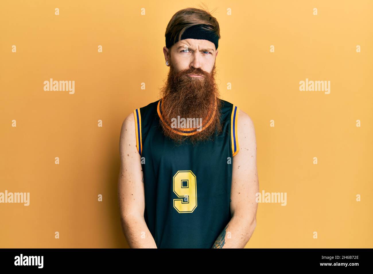 Redhead man with long beard wearing basketball uniform depressed and ...