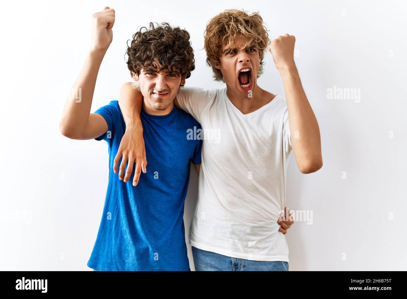 Young gay couple standing together over isolated background angry and ...