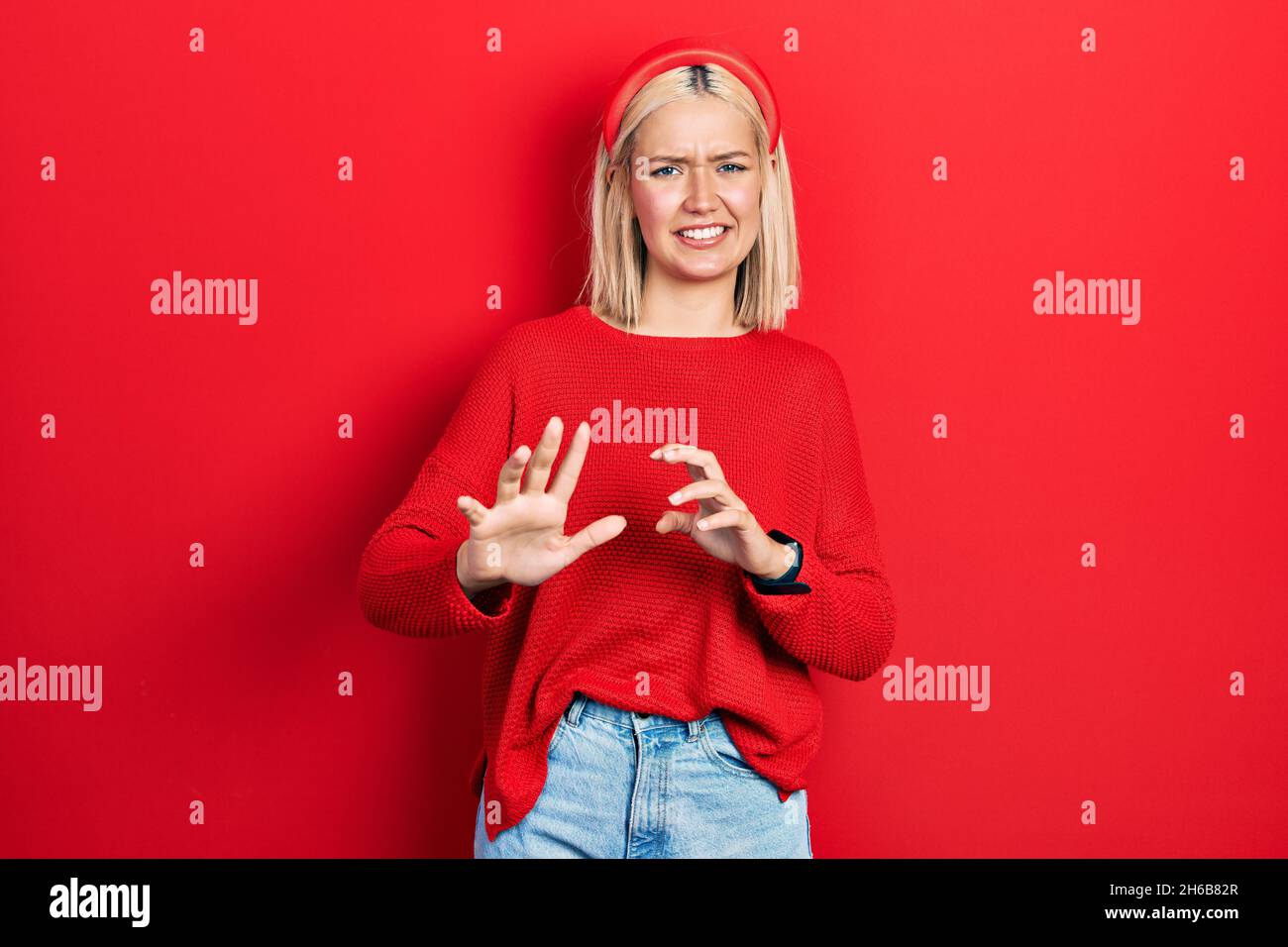 Beautiful blonde woman wearing casual red sweater disgusted expression ...