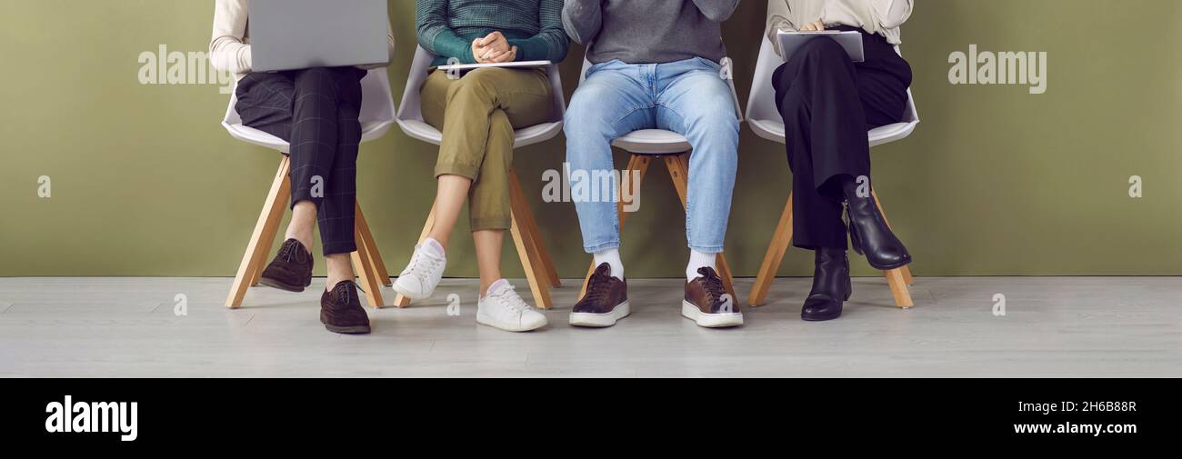 Legs of four job applicants sitting on chairs in hallway waiting in ...