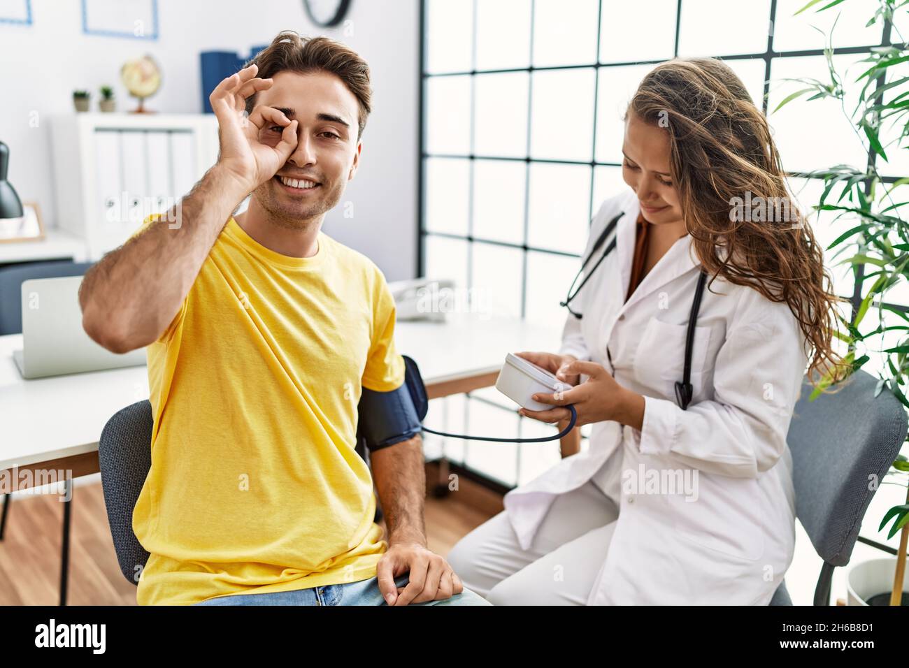 Young doctor woman checking blood pressure on patient smiling happy ...