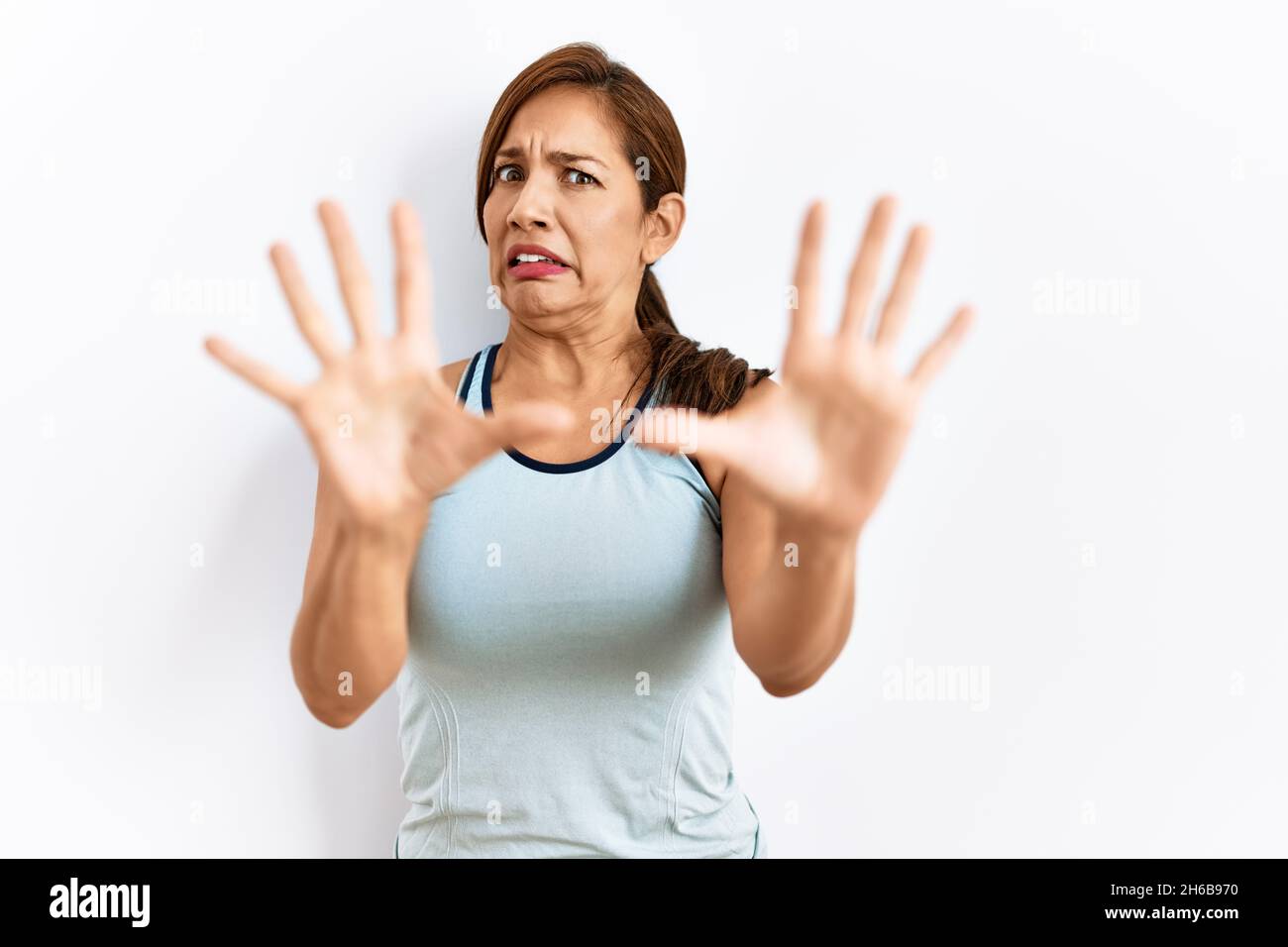 Young latin woman wearing sporty clothes over isolated background ...
