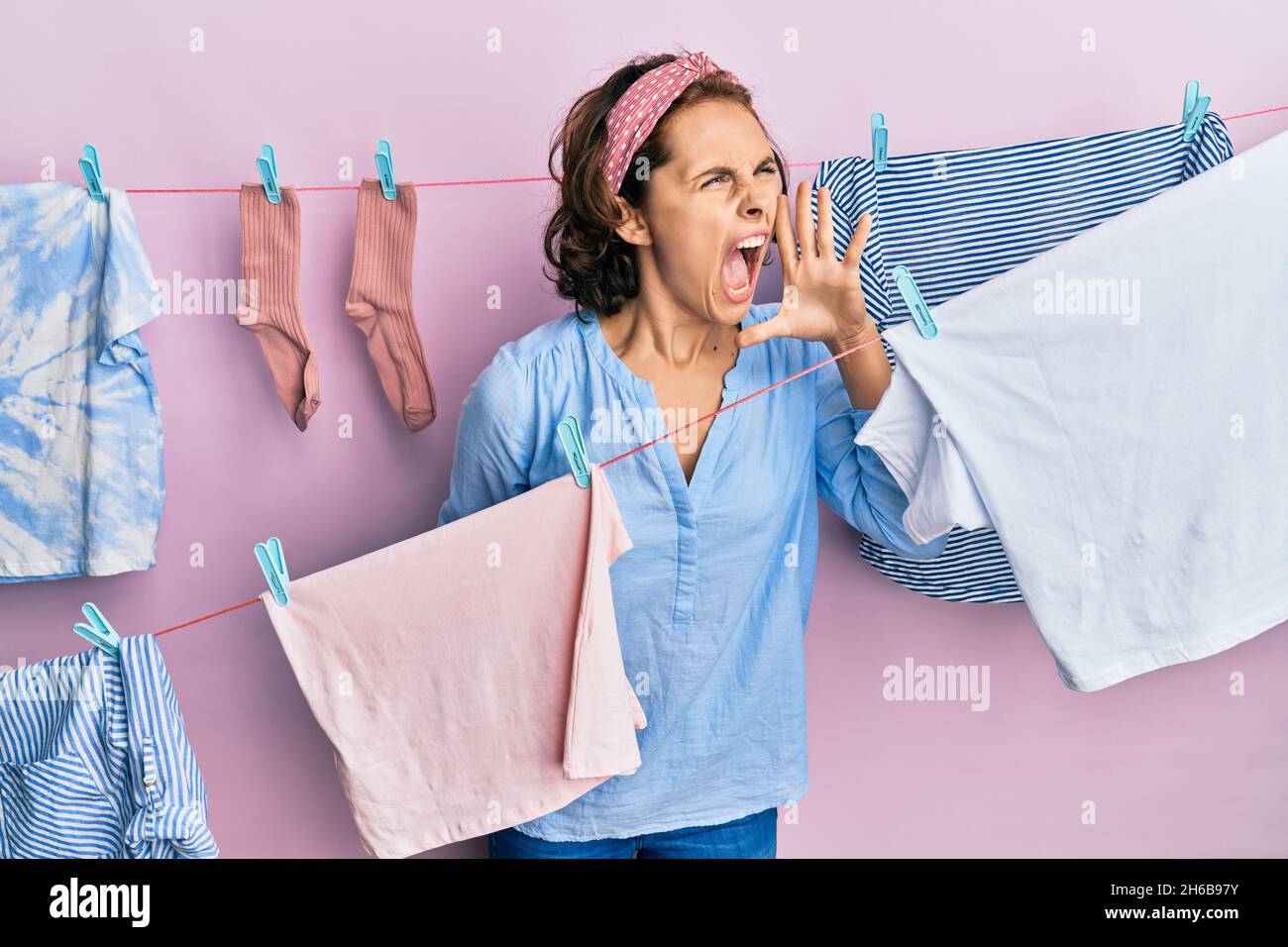 Young brunette woman doing laundry around string hangs shouting and ...