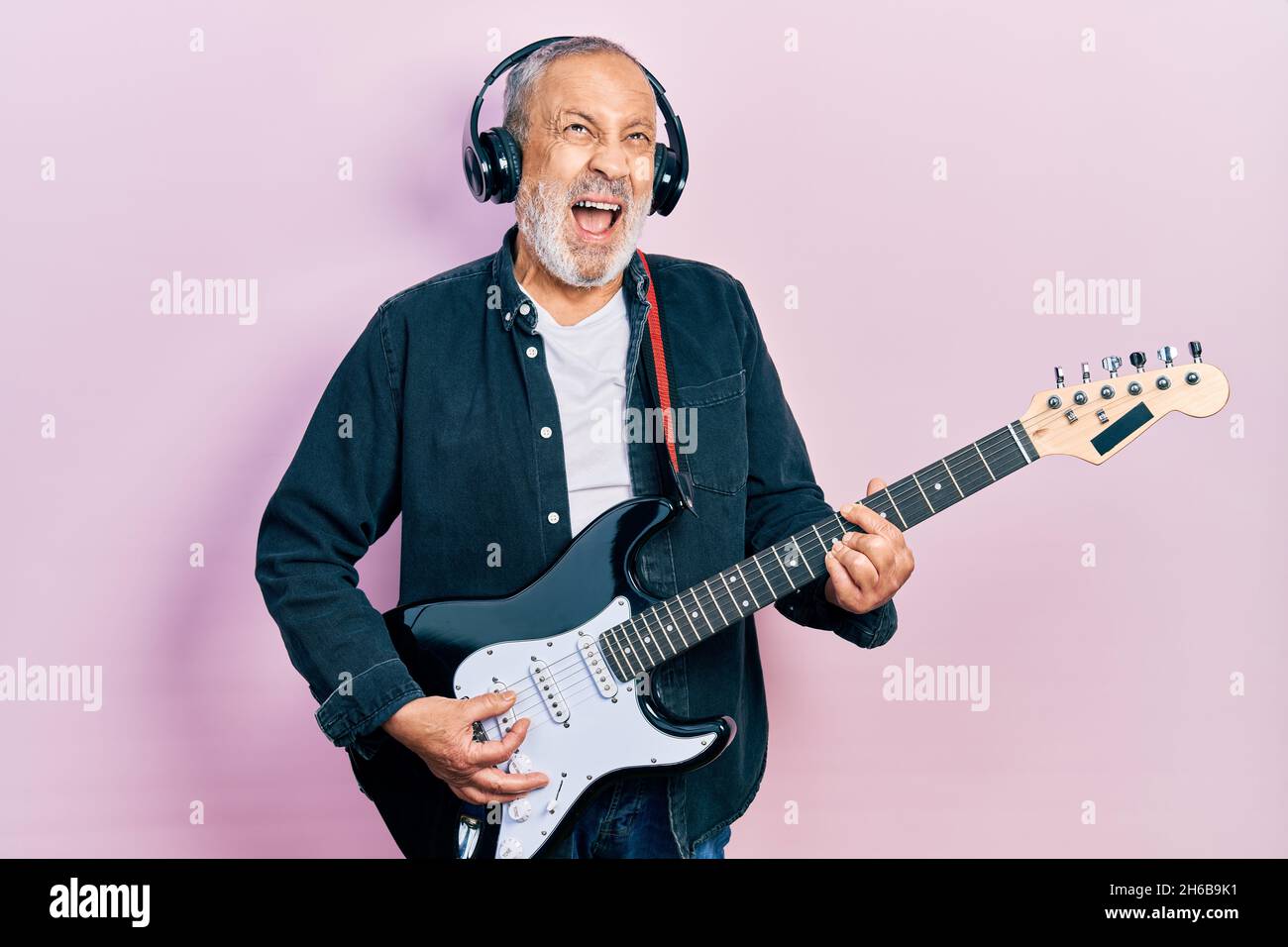 Handsome senior man with beard playing electric guitar angry and mad ...