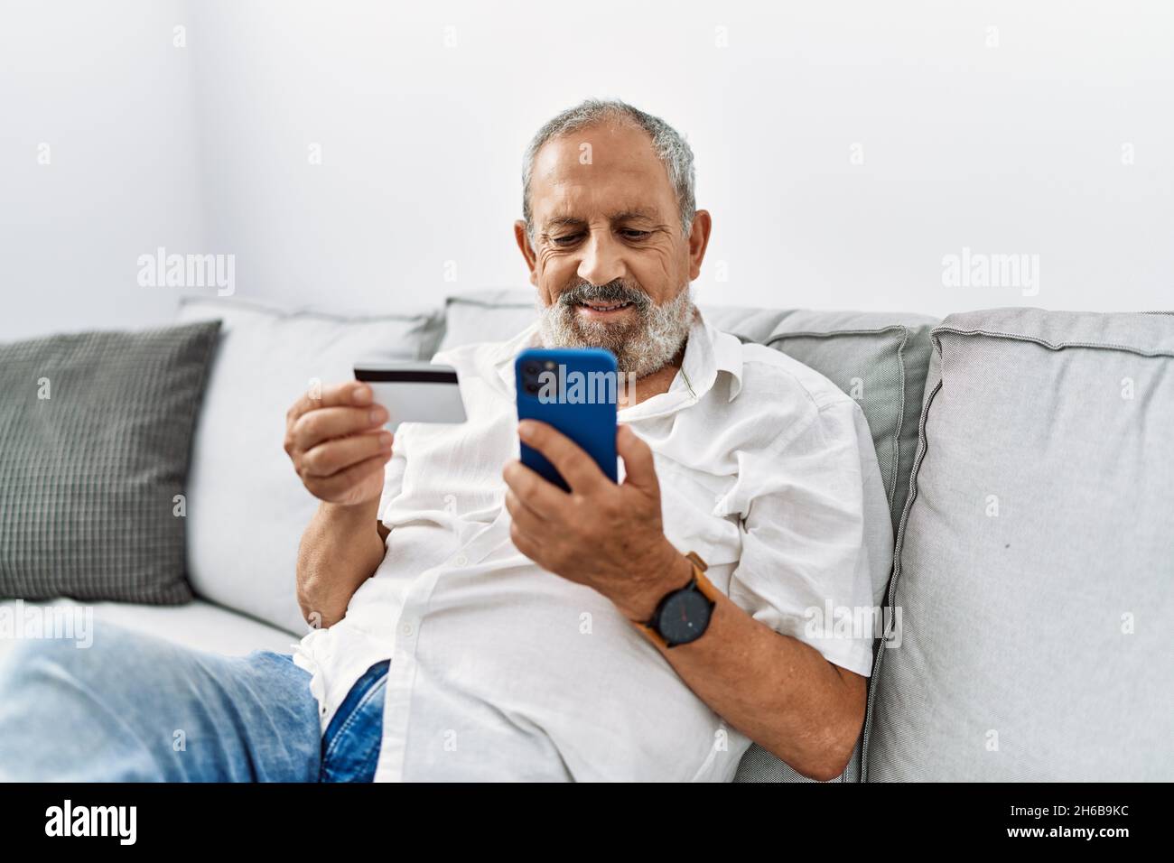Senior grey-haired man smiling confident using smartphone and credit ...