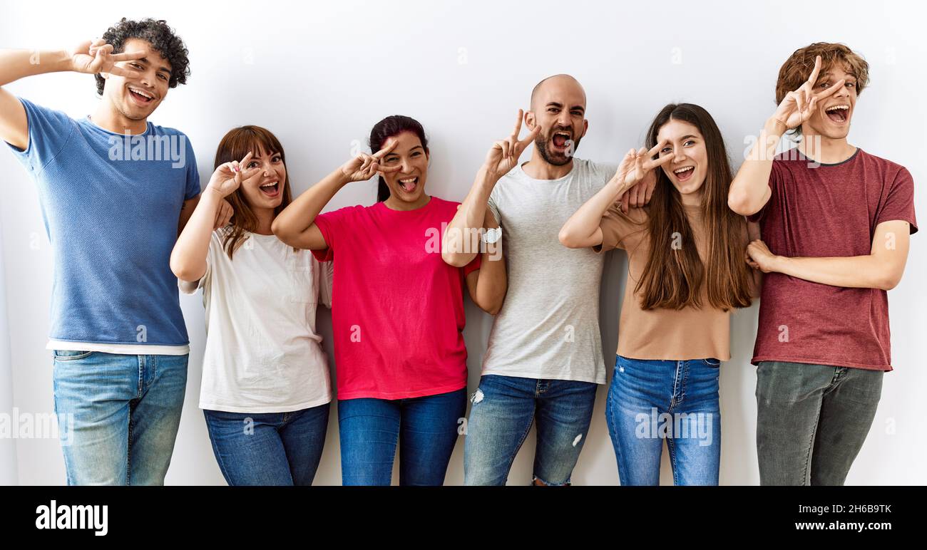 Group of young friends standing together over isolated background doing ...